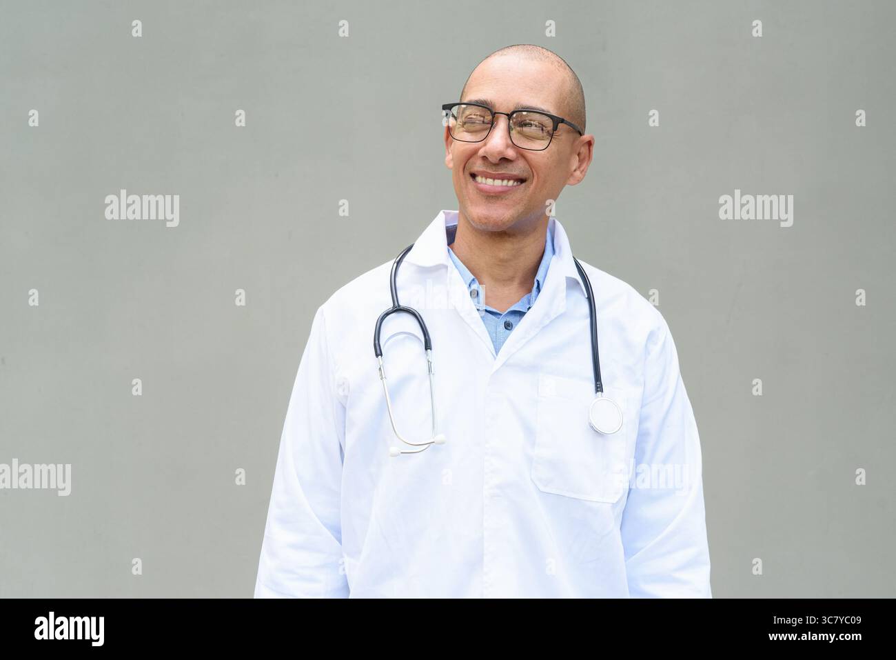 Portrait of mature bald male doctor wearing lab coat and eyeglasses ...