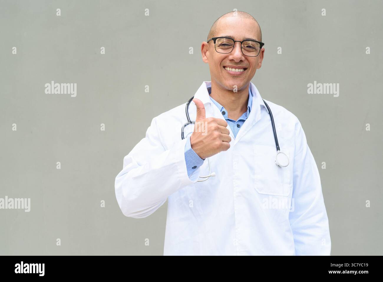 Portrait of mature bald male doctor wearing lab coat and eyeglasses ...