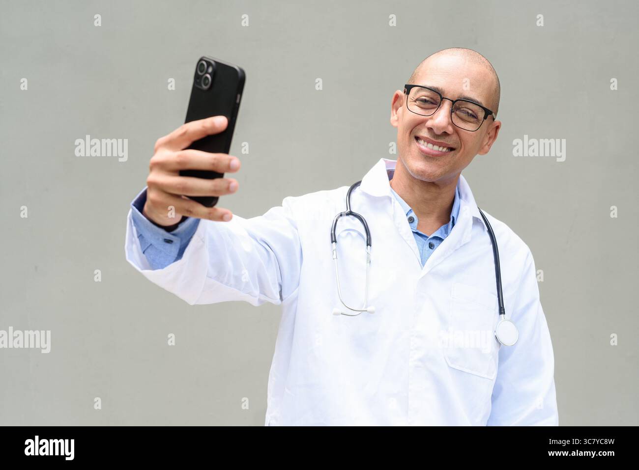 Portrait of mature bald male doctor wearing lab coat and eyeglasses ...