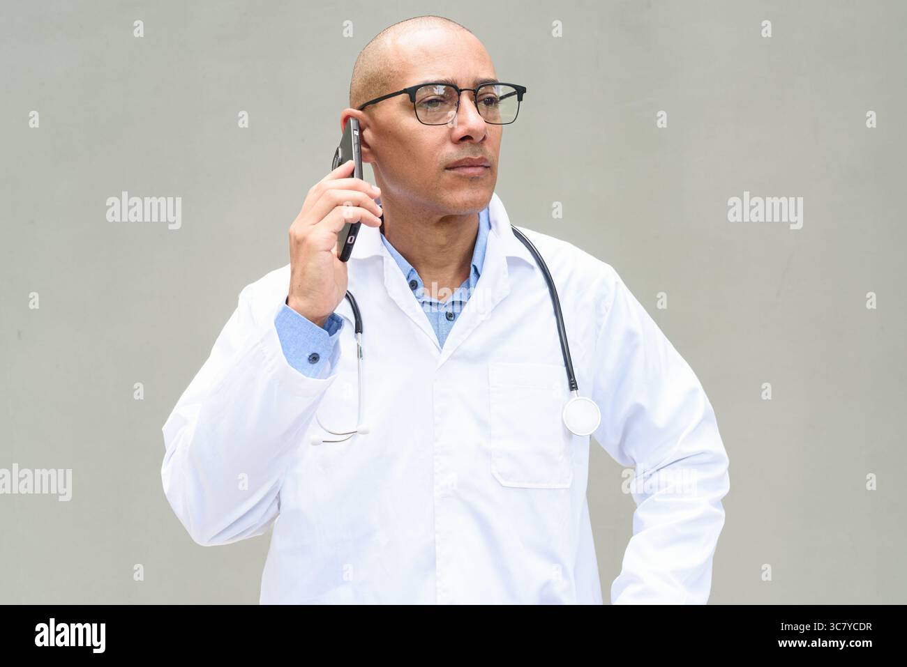 Portrait of mature bald male doctor wearing lab coat and eyeglasses ...
