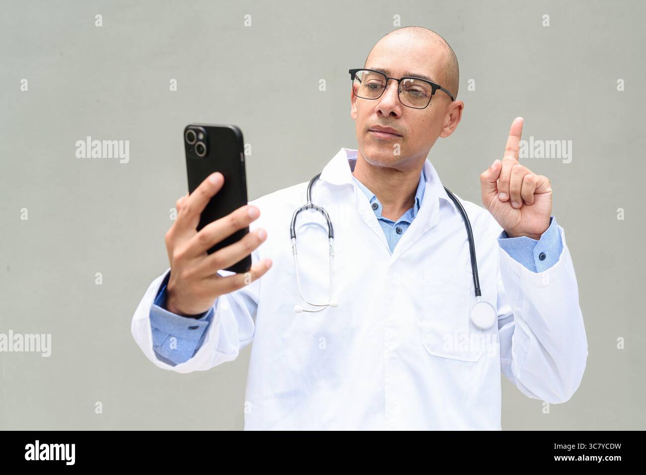 Portrait of mature bald male doctor wearing lab coat and eyeglasses ...