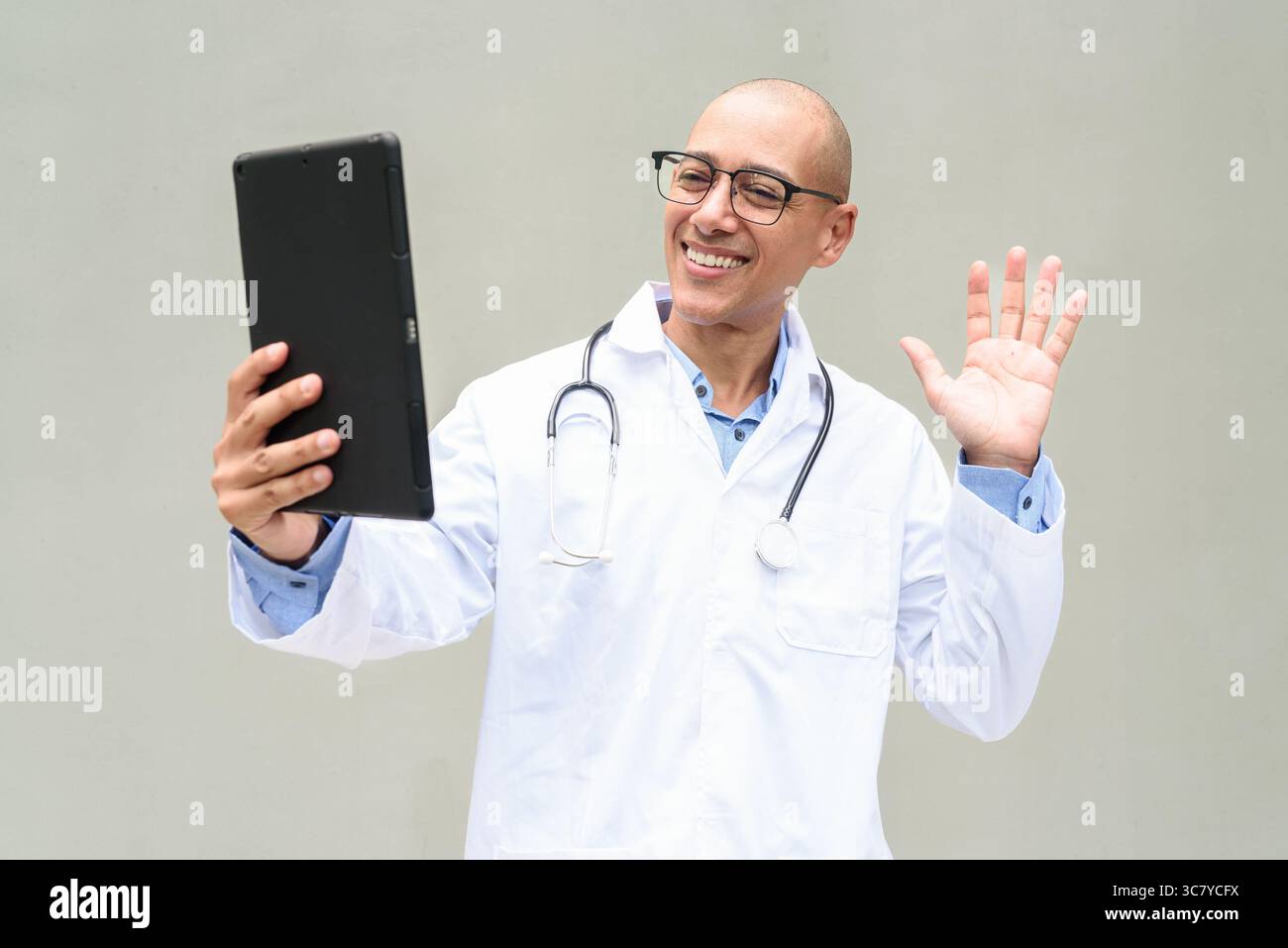 Portrait of mature bald male doctor wearing lab coat and eyeglasses ...