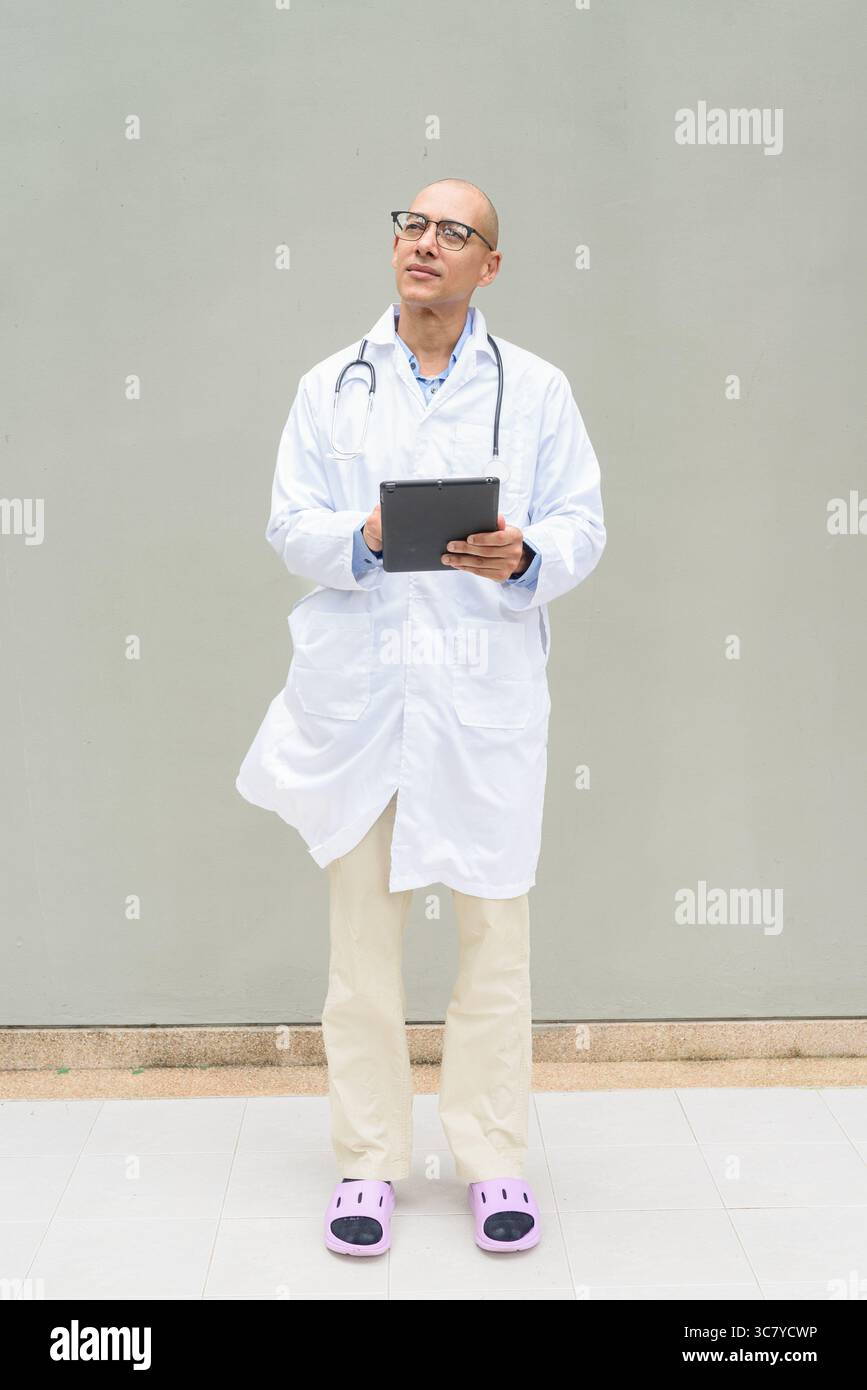 Portrait of mature bald male doctor wearing lab coat and eyeglasses ...