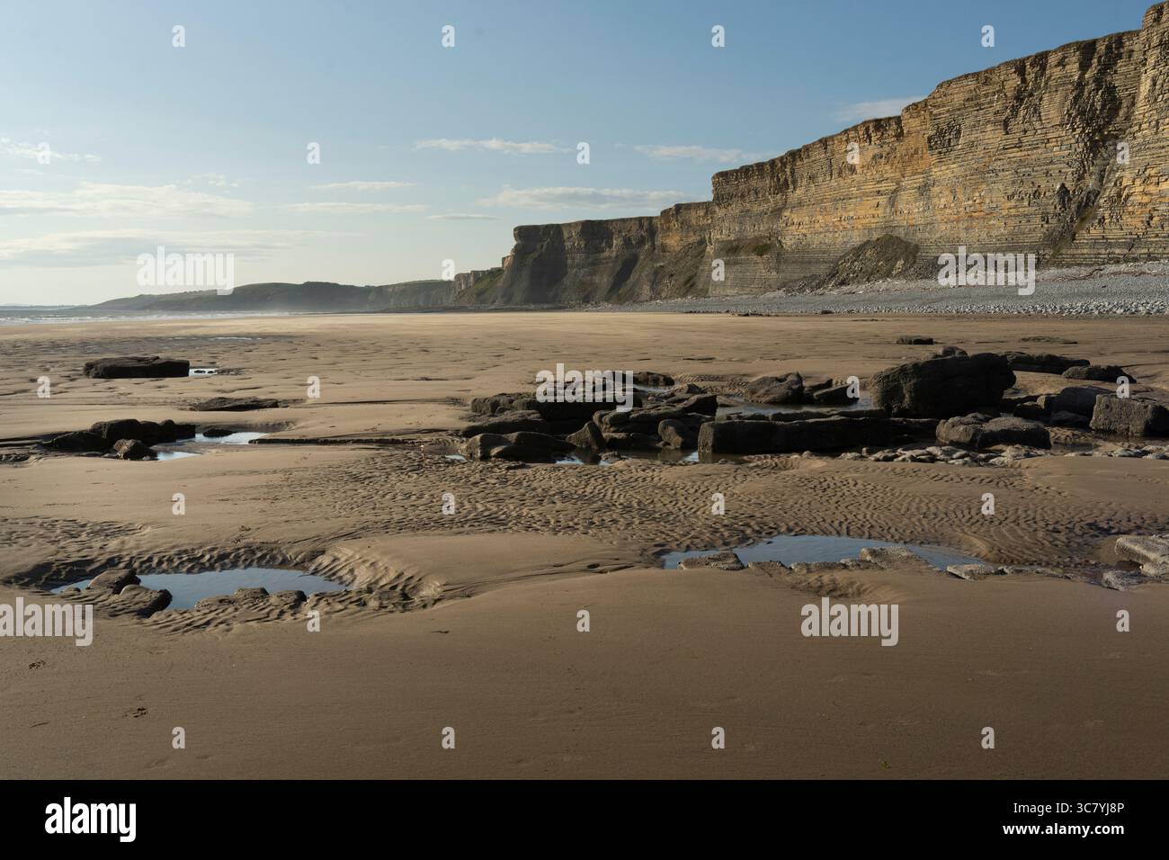 Low tide reveals rock pools and patterns in the sand at Monknash beach ...