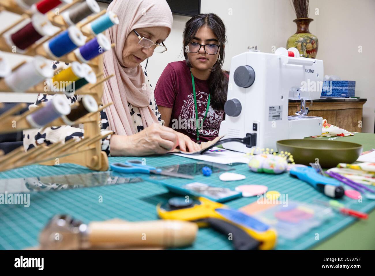 Amal Alalim helps student Sana Abawi, 12, in a sewing class at Olive ...