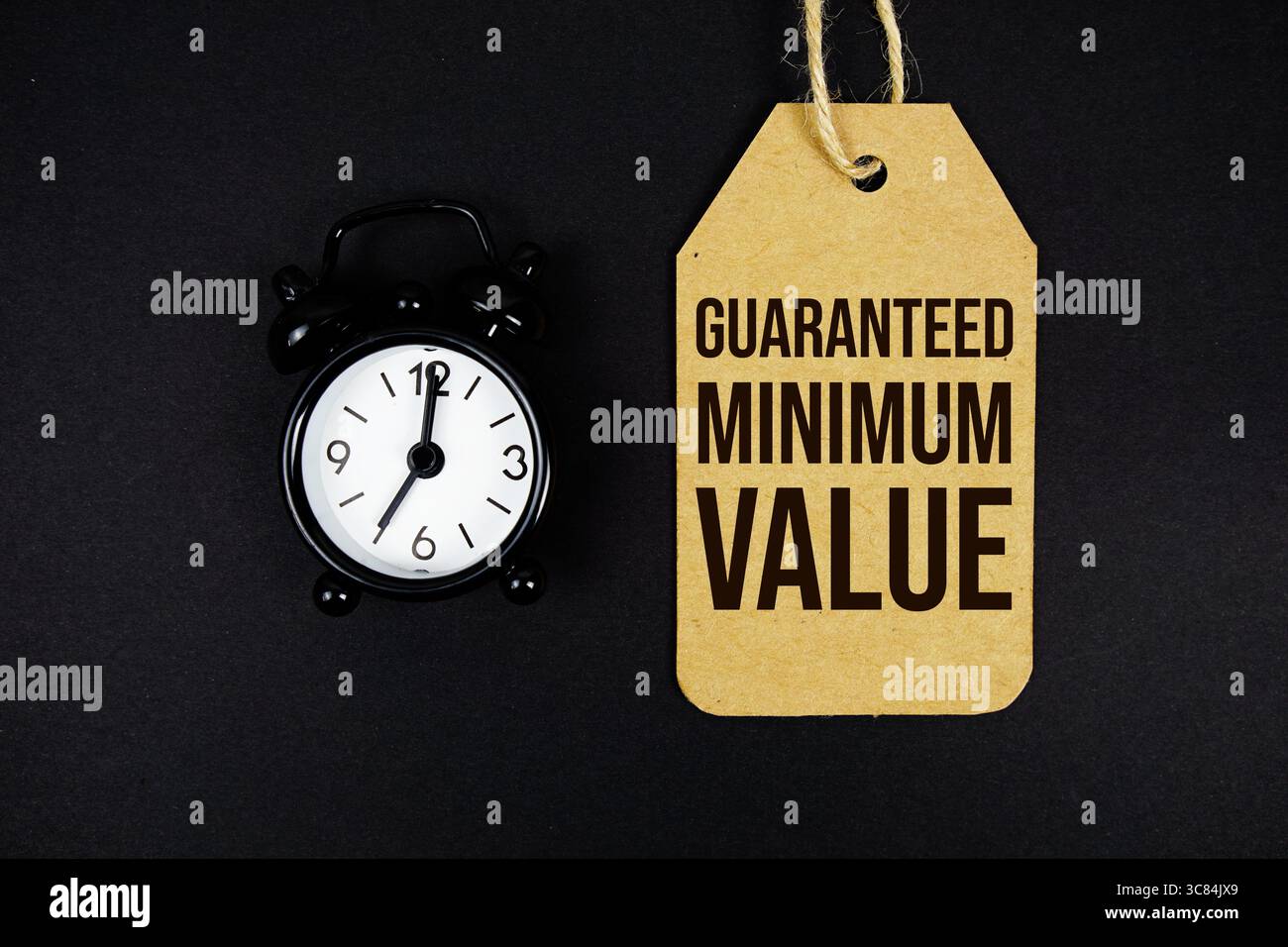 Guaranteed Minimum Value text on price tag with alarm clock on black ...