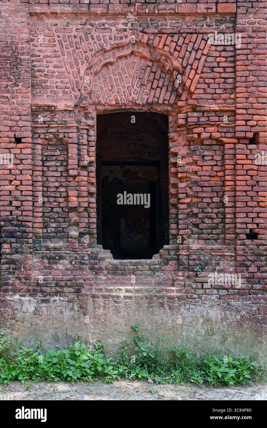 Weathered wooden door framed by old brick arches inside an abandoned ...