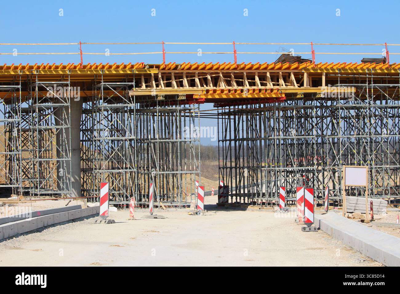 A major bridge under assembly spans a construction zone, supported by ...
