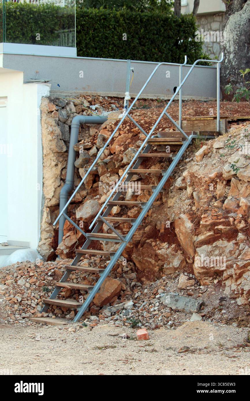 A steep, metal-framed temporary staircase ascends a rocky, excavated ...
