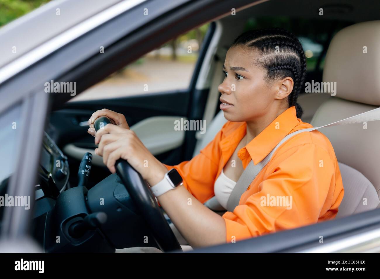 Worried young african american woman driving car with tense expression ...