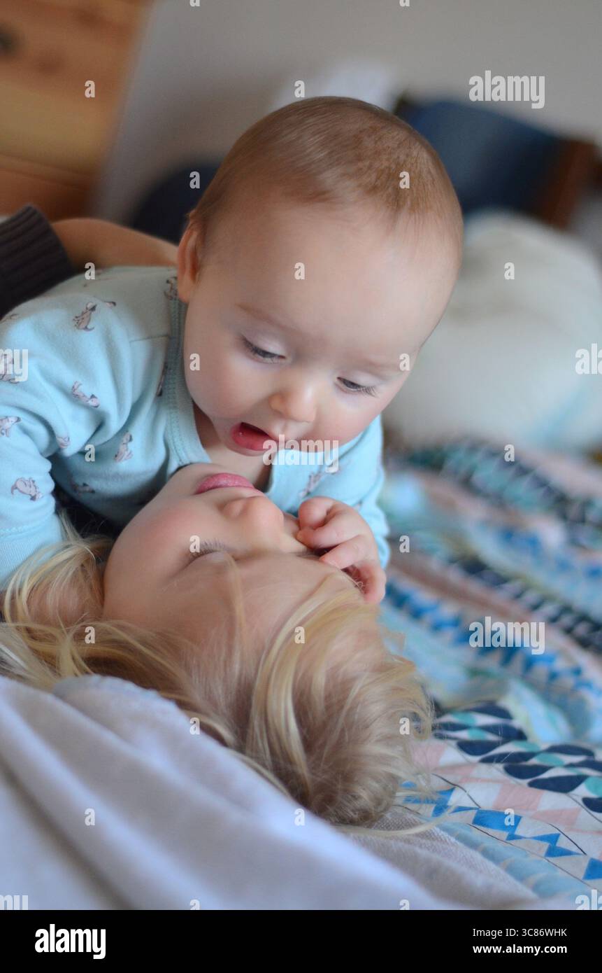 A tender moment captured as a baby gently cuddles with an older sibling ...