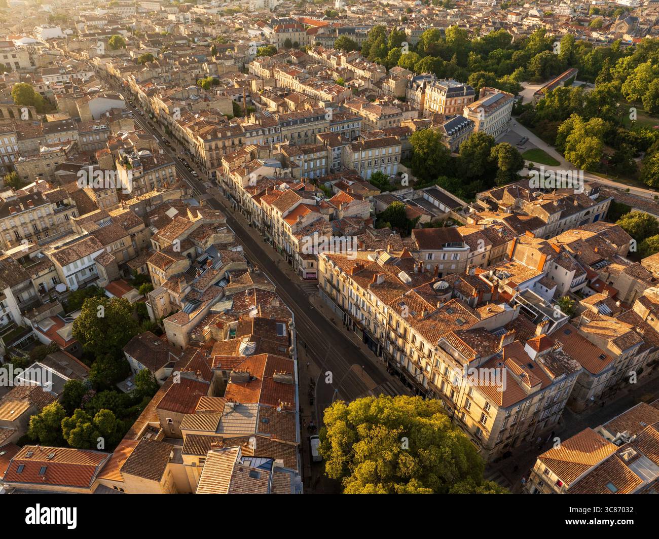 Aerial view of sun-kissed rooftops create a warm mosaic, bisected by a ...