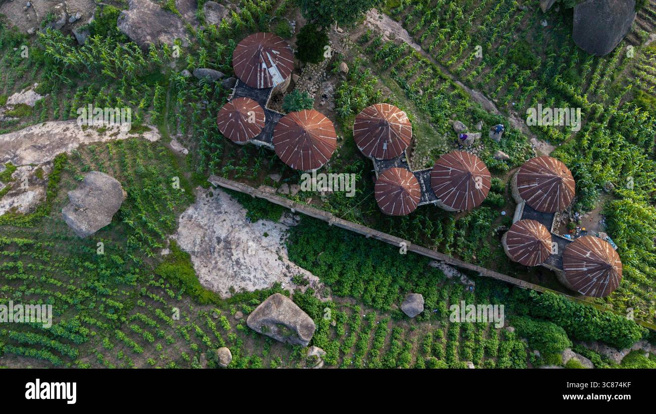 Aerial view of rustic, round huts with rusty roofs nestled among fields ...