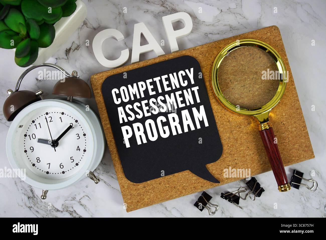 CAP Competency Assessment Program text with alarm clock and magnifying glass on marble ...