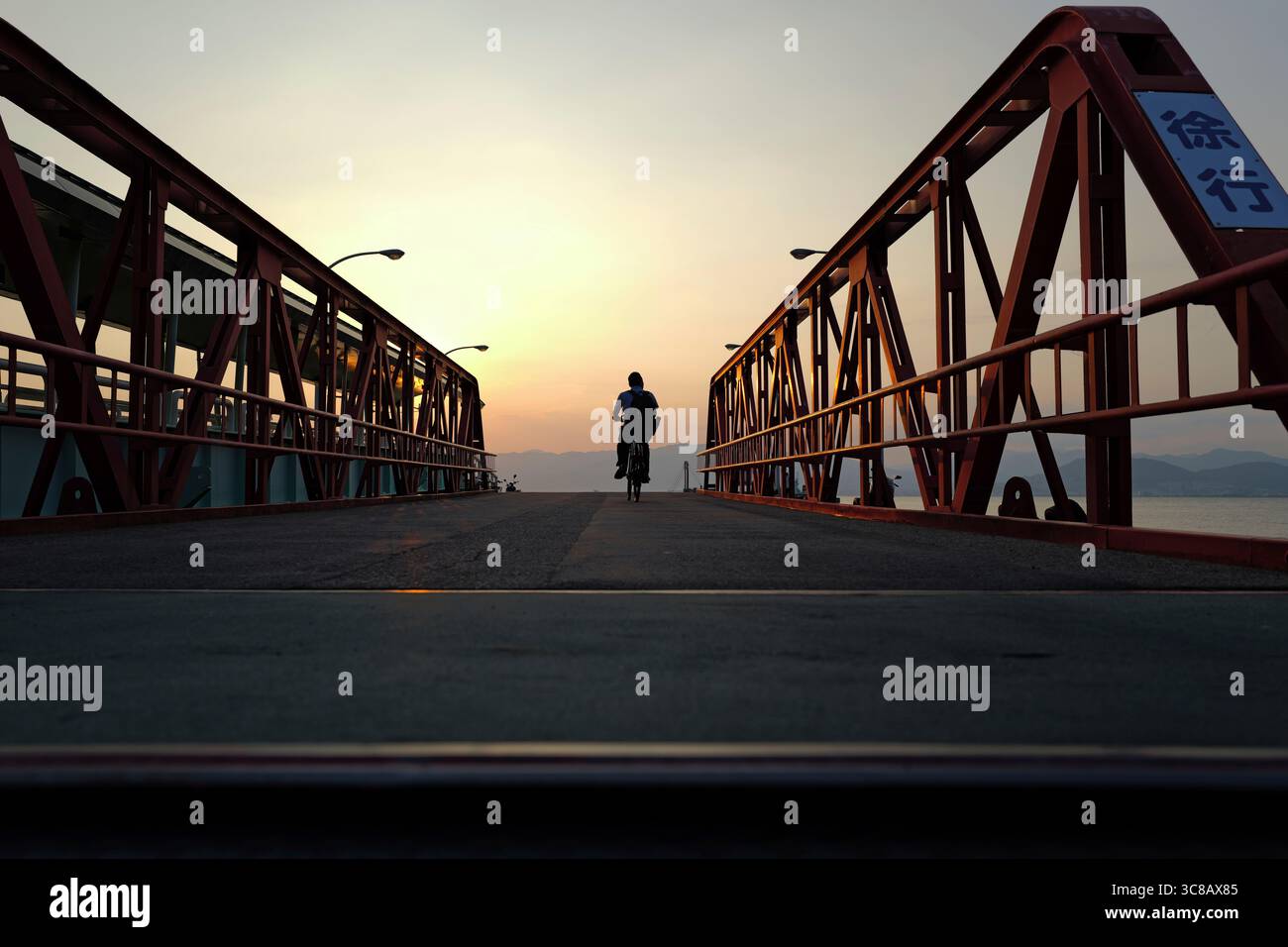 A local worker crosses the pier on a bicycle to catch a ferry in ...