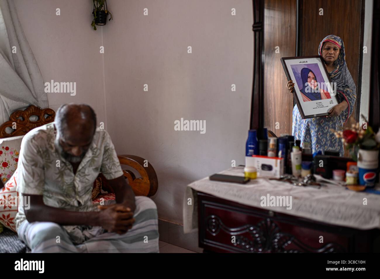 Asma Begum, standing next to her husband, is reflected in a mirror as ...