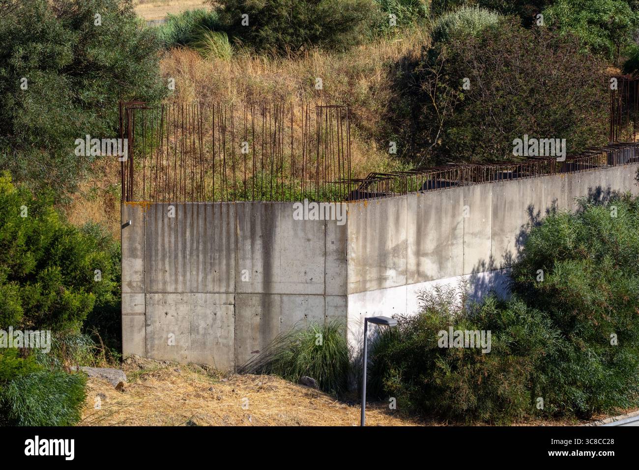Rusty metal fence protruding from a concrete wall structure ...