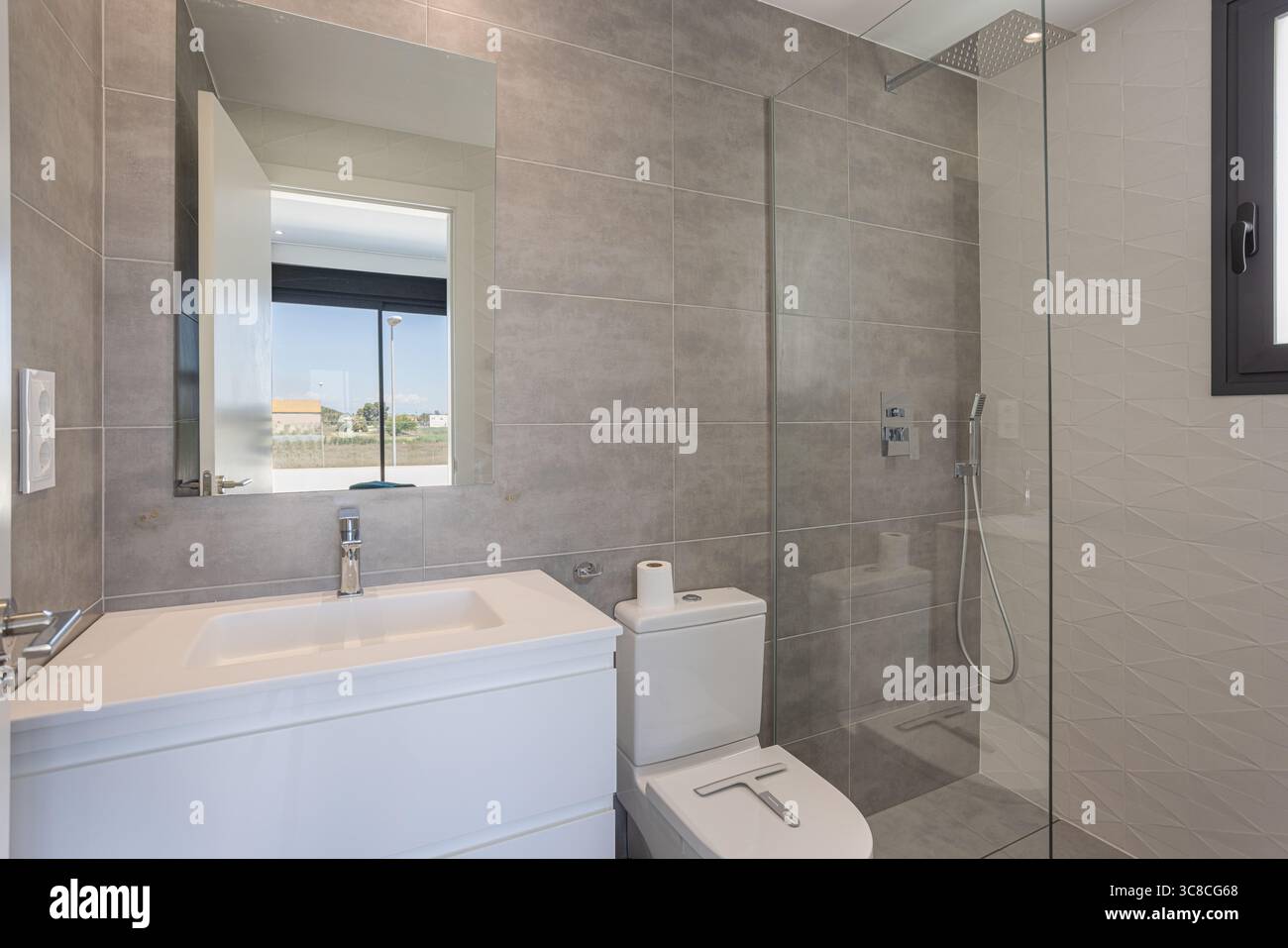 Stylish bathroom with grey tiled walls, walk-in glass shower, and sleek ...