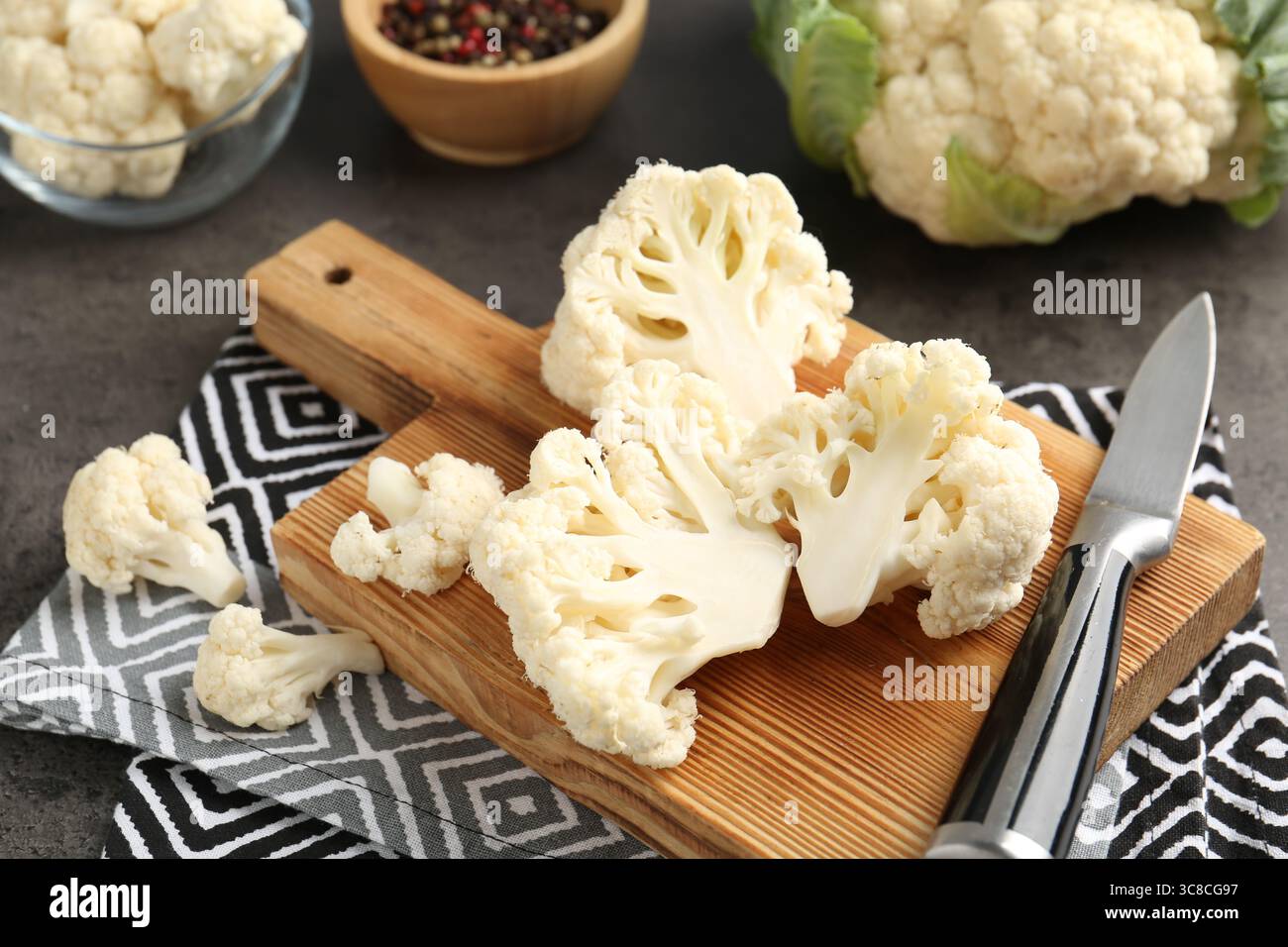 Fresh raw cauliflower florets, spices and knife on grey table, closeup ...