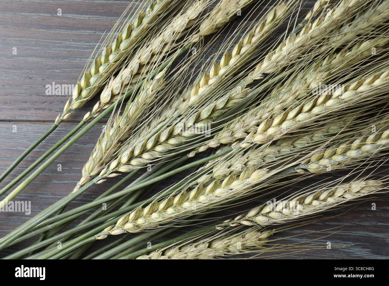 Green wheat spikes on wooden table, above view Stock Photo - Alamy