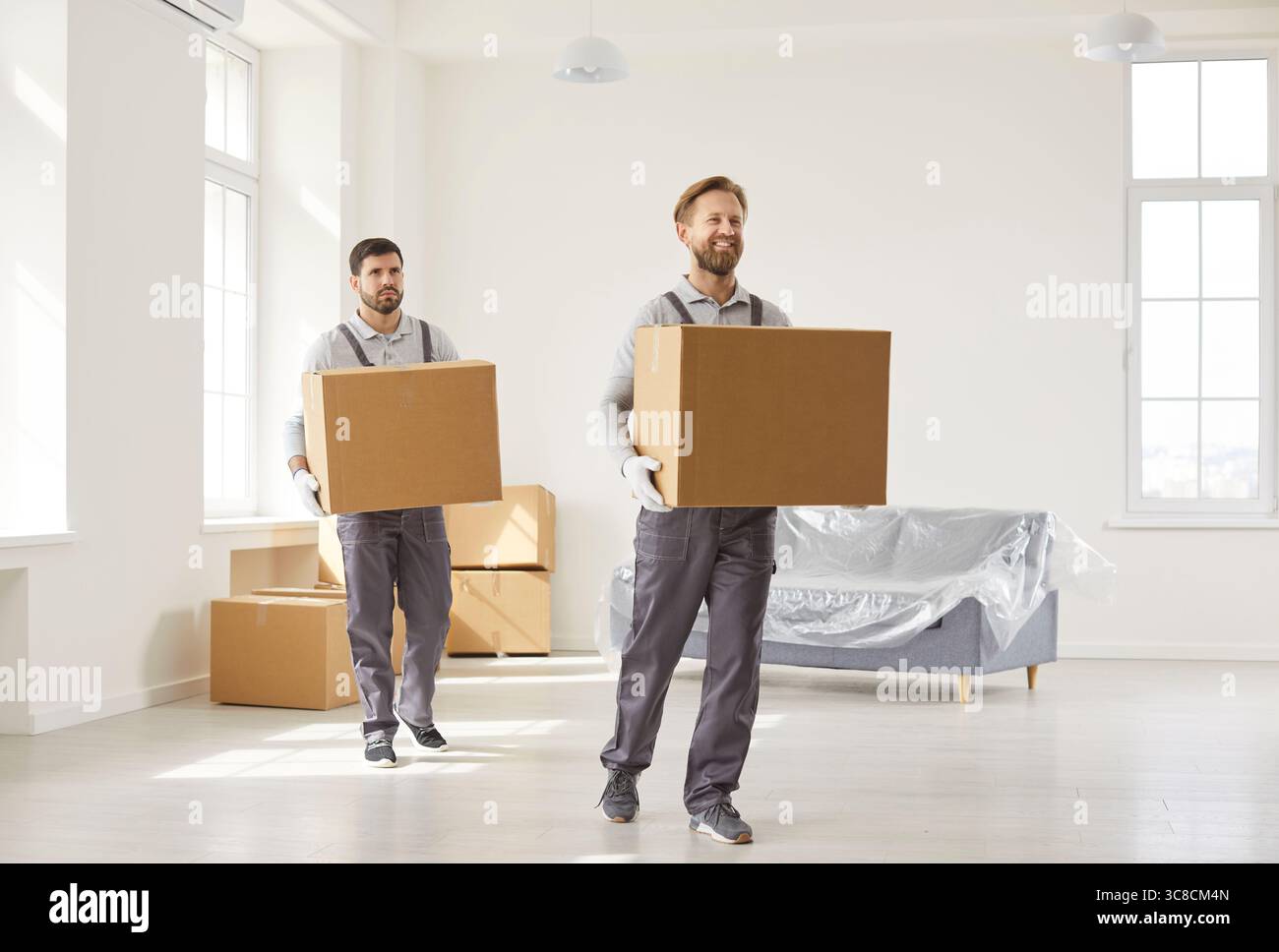 Two busy man movers carrying cardboard boxes with belongings, working ...