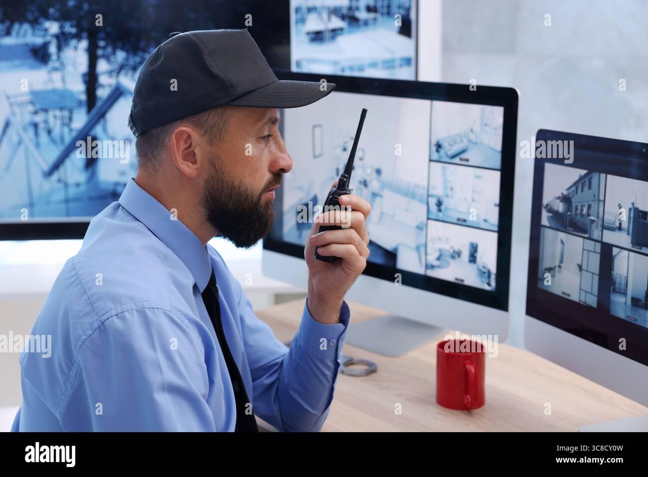 Security guard monitoring CCTV cameras and using walkie talkie in ...