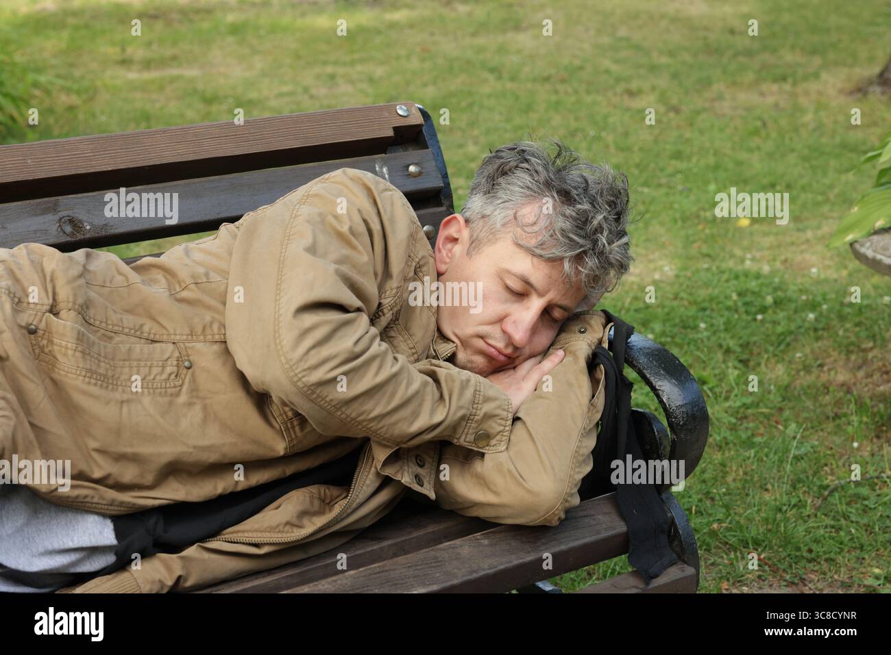 Homeless man sleeping on bench in park Stock Photo - Alamy