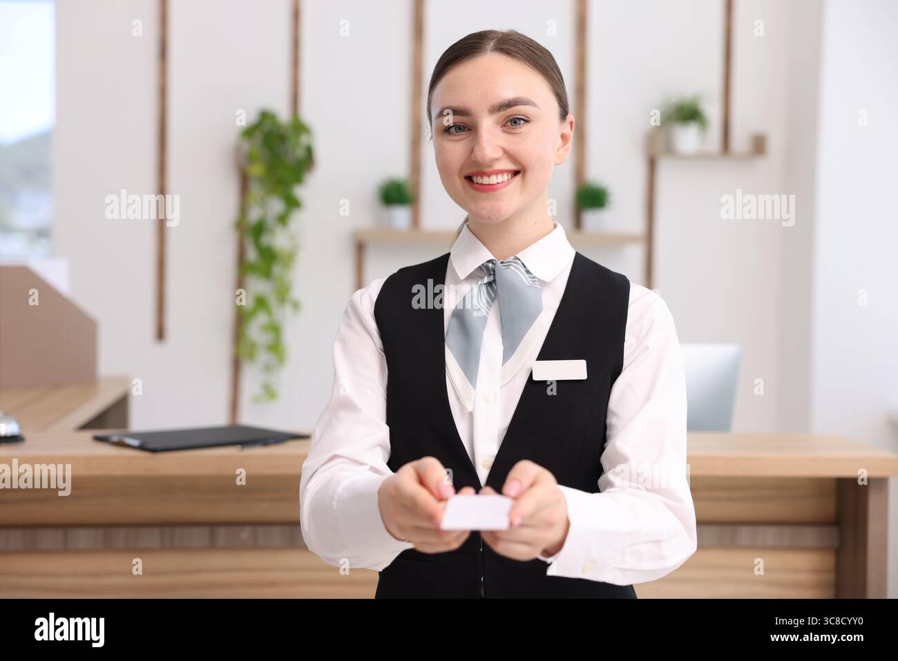 Portrait of smiling receptionist giving hotel key card indoors Stock ...