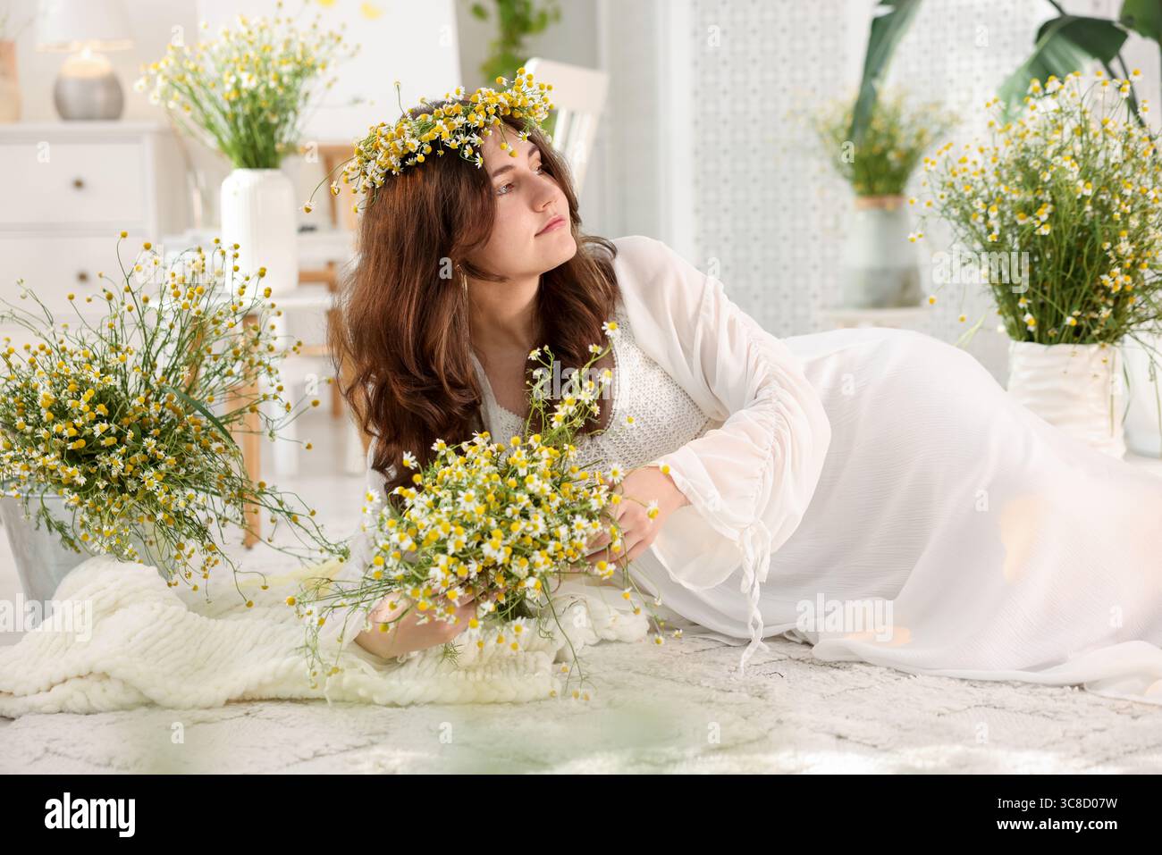 Beautiful woman with chamomile flowers on floor indoors Stock Photo - Alamy