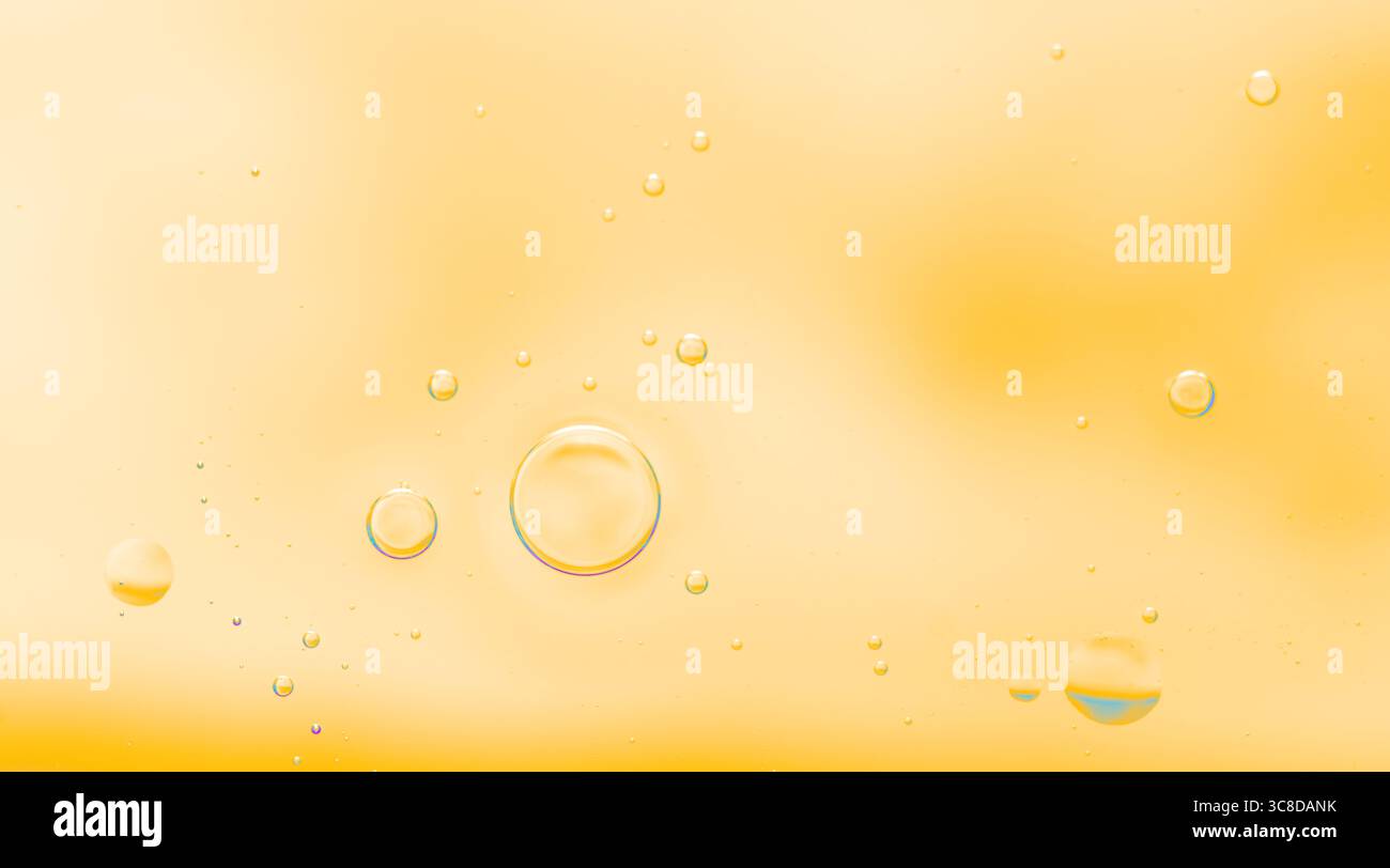 Soft abstract close-up of oil bubbles floating in warm golden-yellow ...