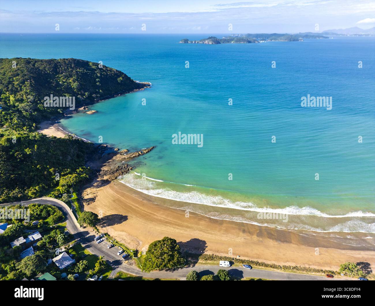 Aerial view of golden sands meeting turquoise waters, lush green hills ...
