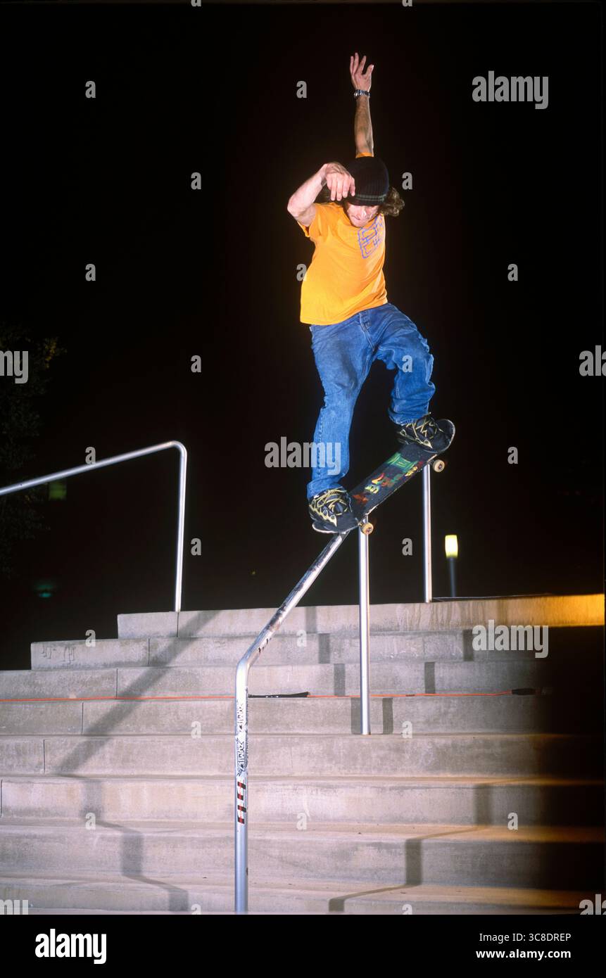 A skateboarder doing a trick (crooked grind) down a tall silver ...
