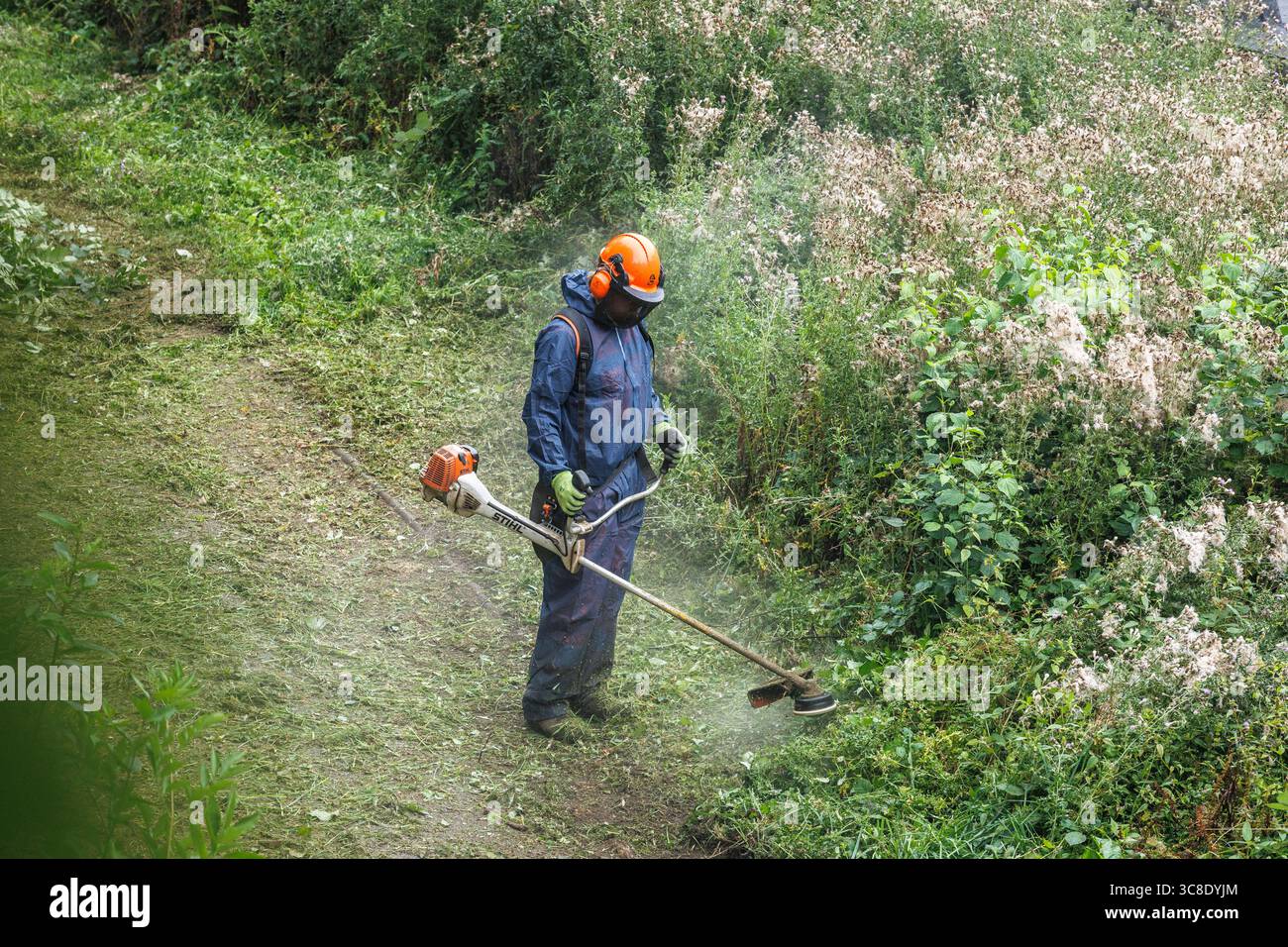 worker with a brushcutter in a public park in the city of Wetter, North ...