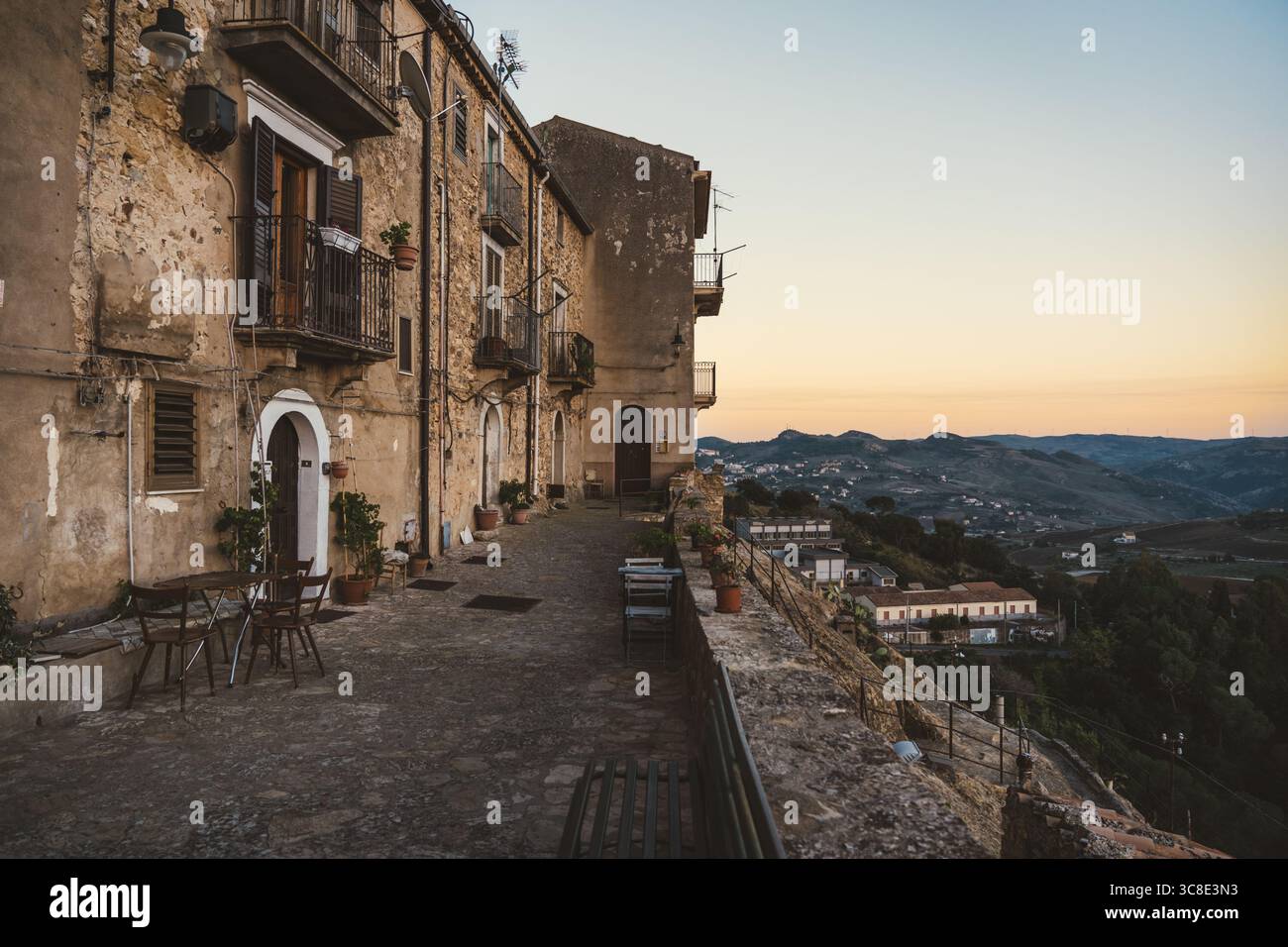 Rustic alley with stone houses and valley view in a Sicilian hilltop ...