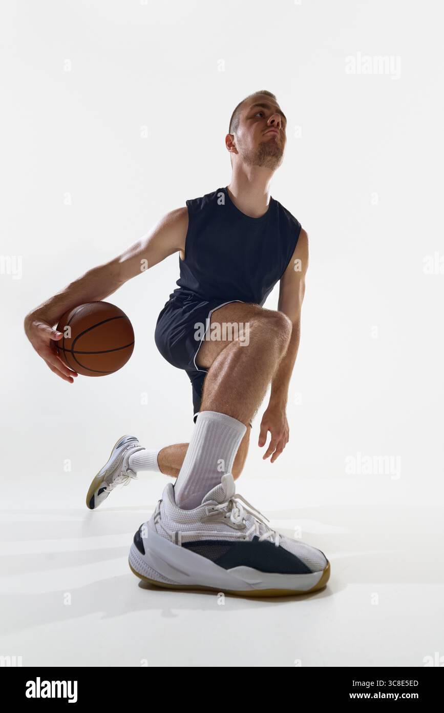 Basketball athlete executing low dribble maneuver on white background ...