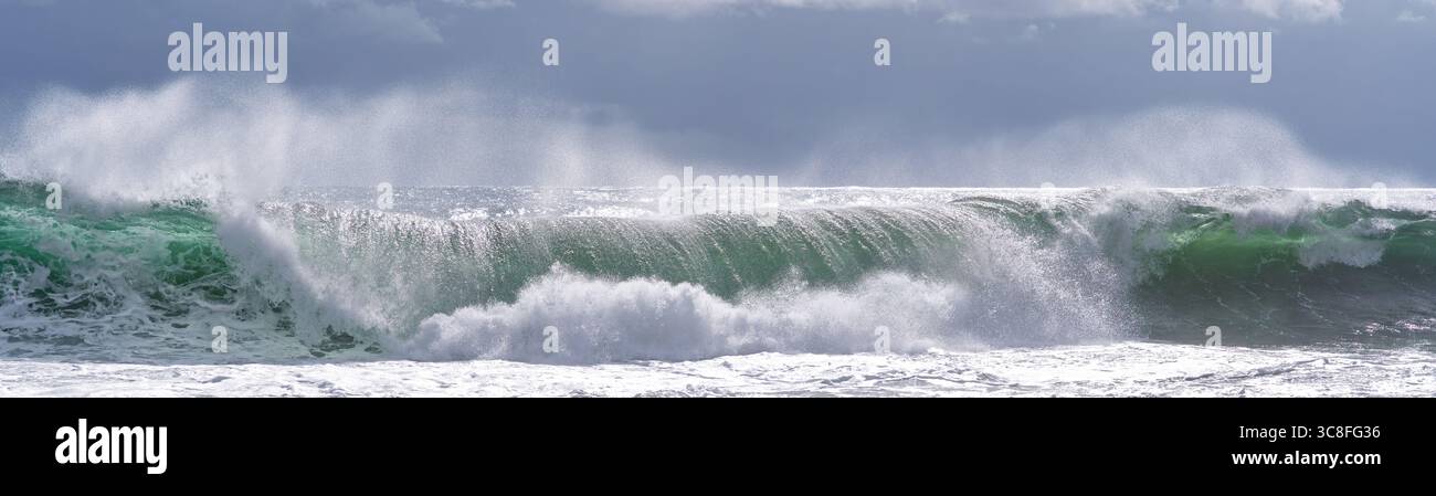 Massive ocean wave breaks with force, sending mist and foam into the ...