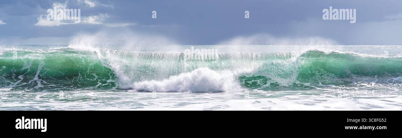 Massive ocean wave breaks with force, sending mist and foam into the ...