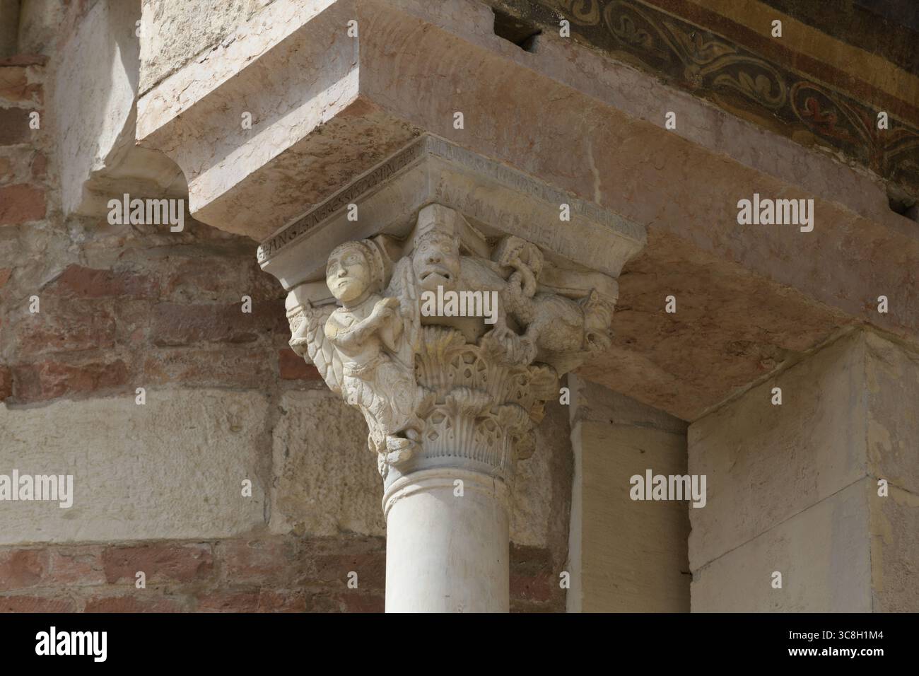 Lateral Romanesque portal with column-bearing lions and faded frescoes ...