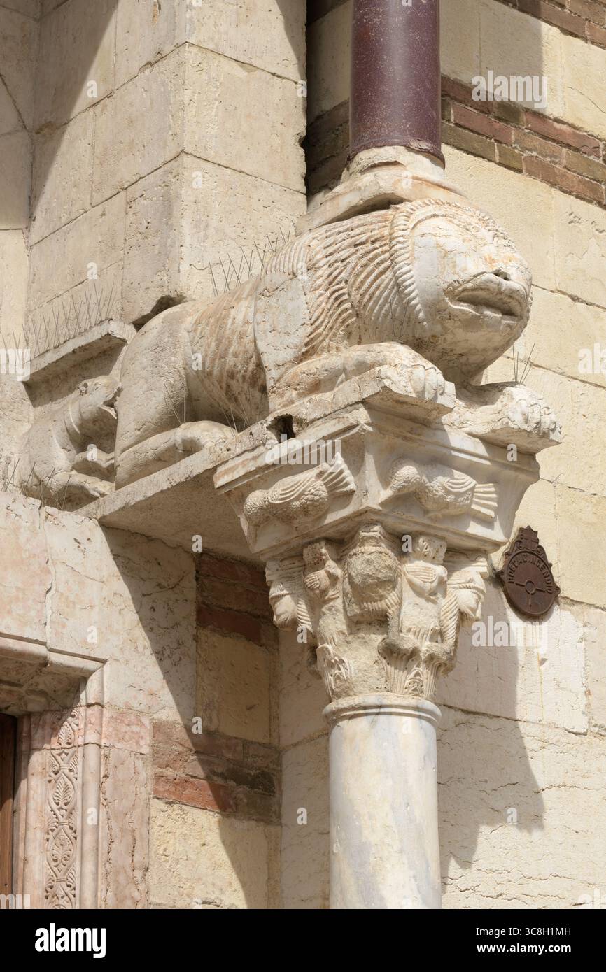 Lateral Romanesque portal with column-bearing lions and faded frescoes ...