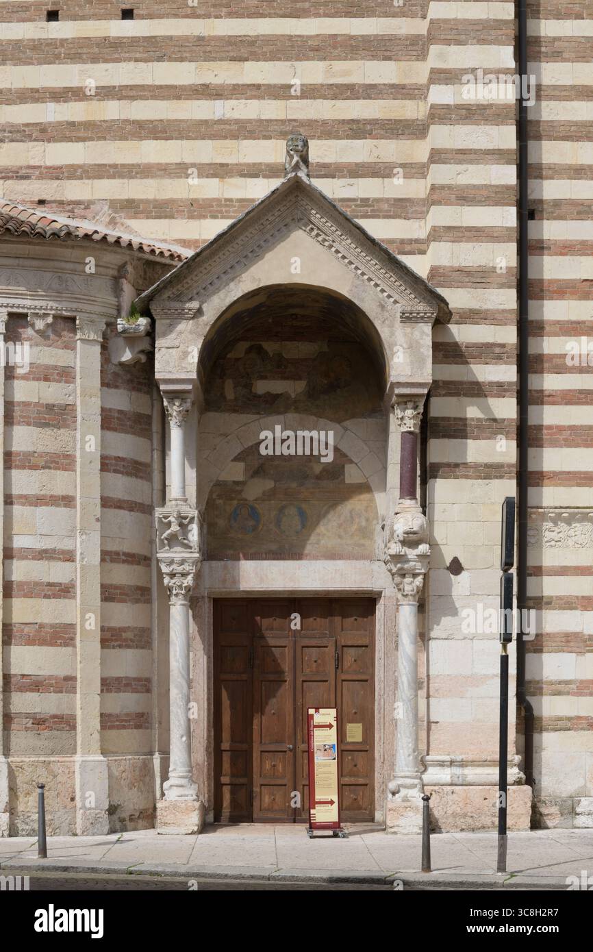 Lateral Romanesque portal with column-bearing lions and faded frescoes ...
