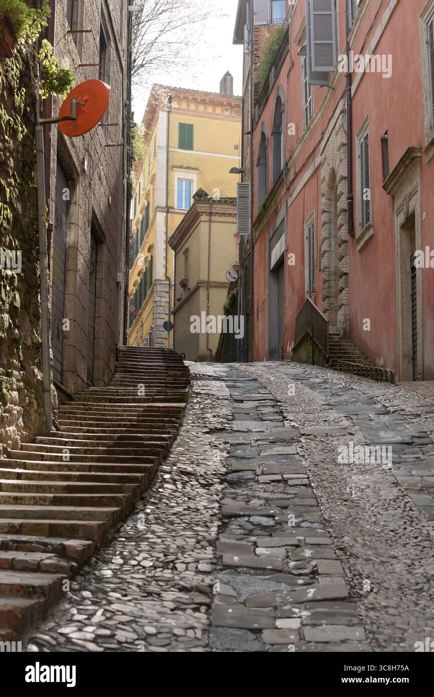 A narrow cobblestone street in Perugia, Italy, featuring a steep ...