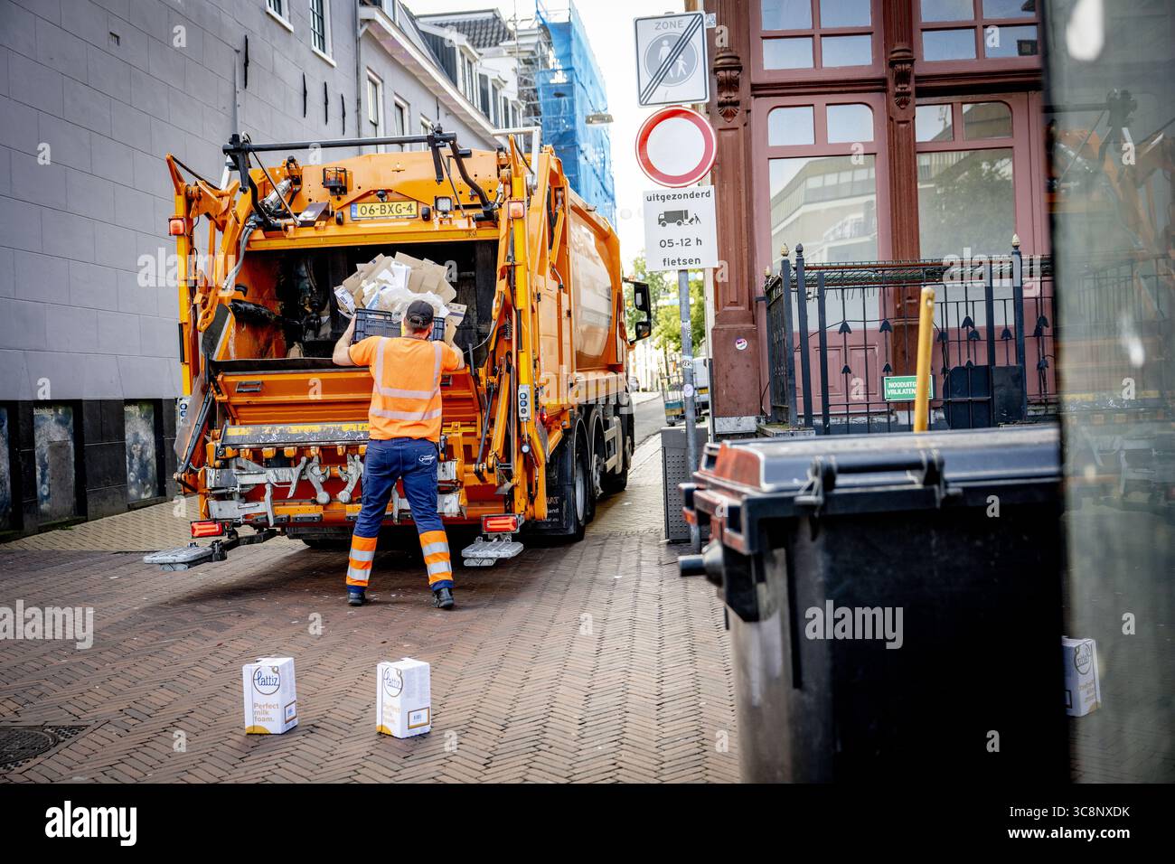 GRONINGEN - Garbage truck in action with garbage men loading and ...