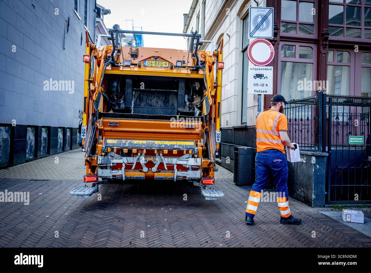 GRONINGEN - Garbage truck in action with garbage men loading and ...