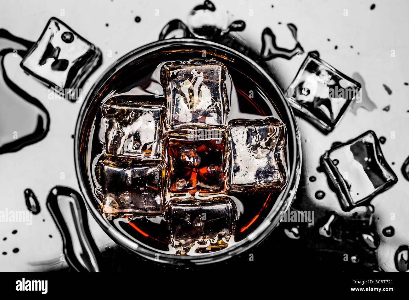 Glass with cola and ice cubes surrounded by ice cubes and water drops ...