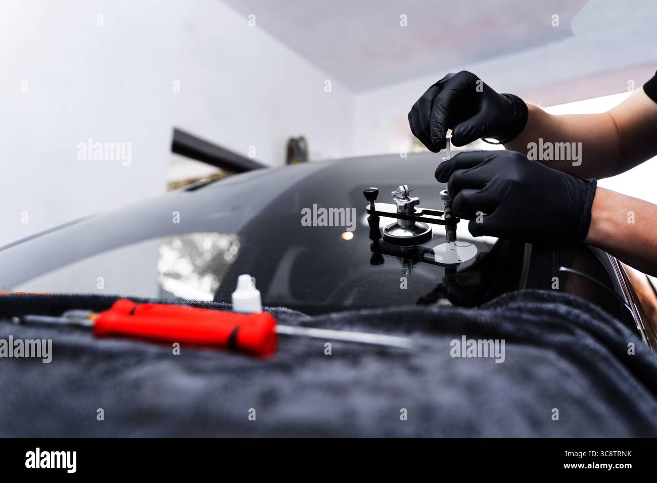 Windshield crack repair using resin injection. Technician using ...