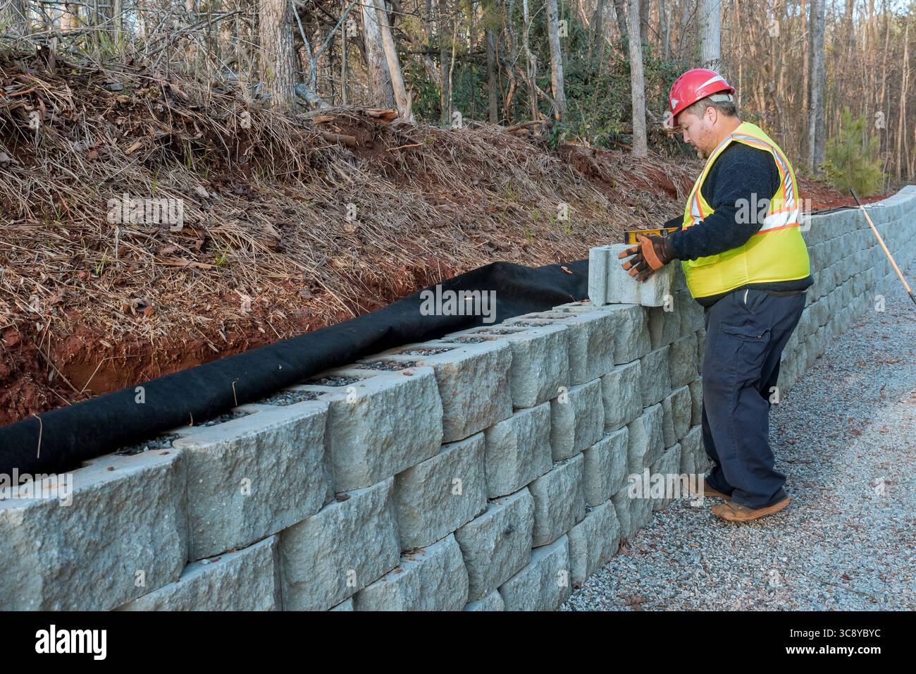 Construction worker carefully places stones to build sturdy wall ...
