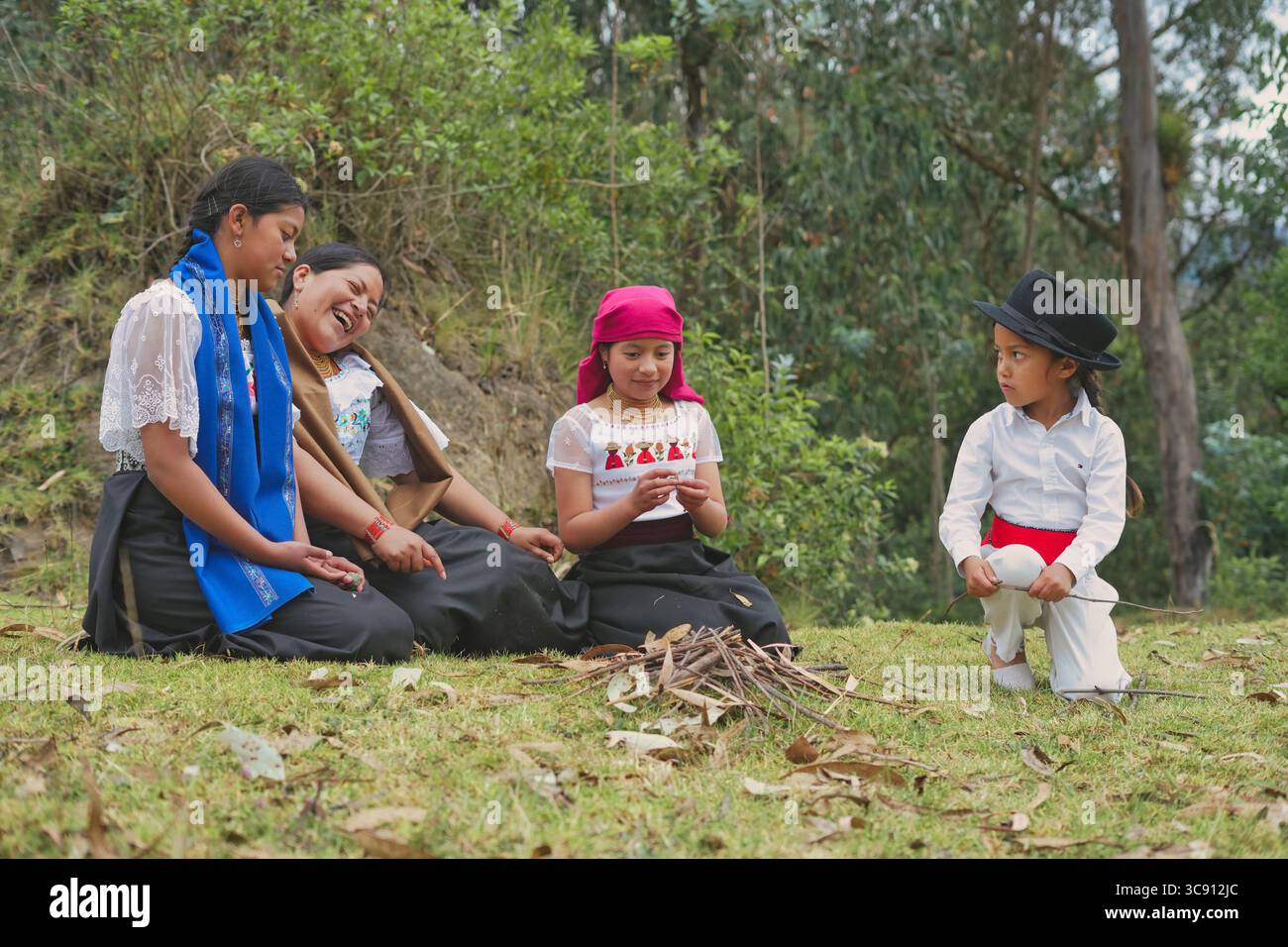 Indigenous family wearing traditional clothes gathering around small ...