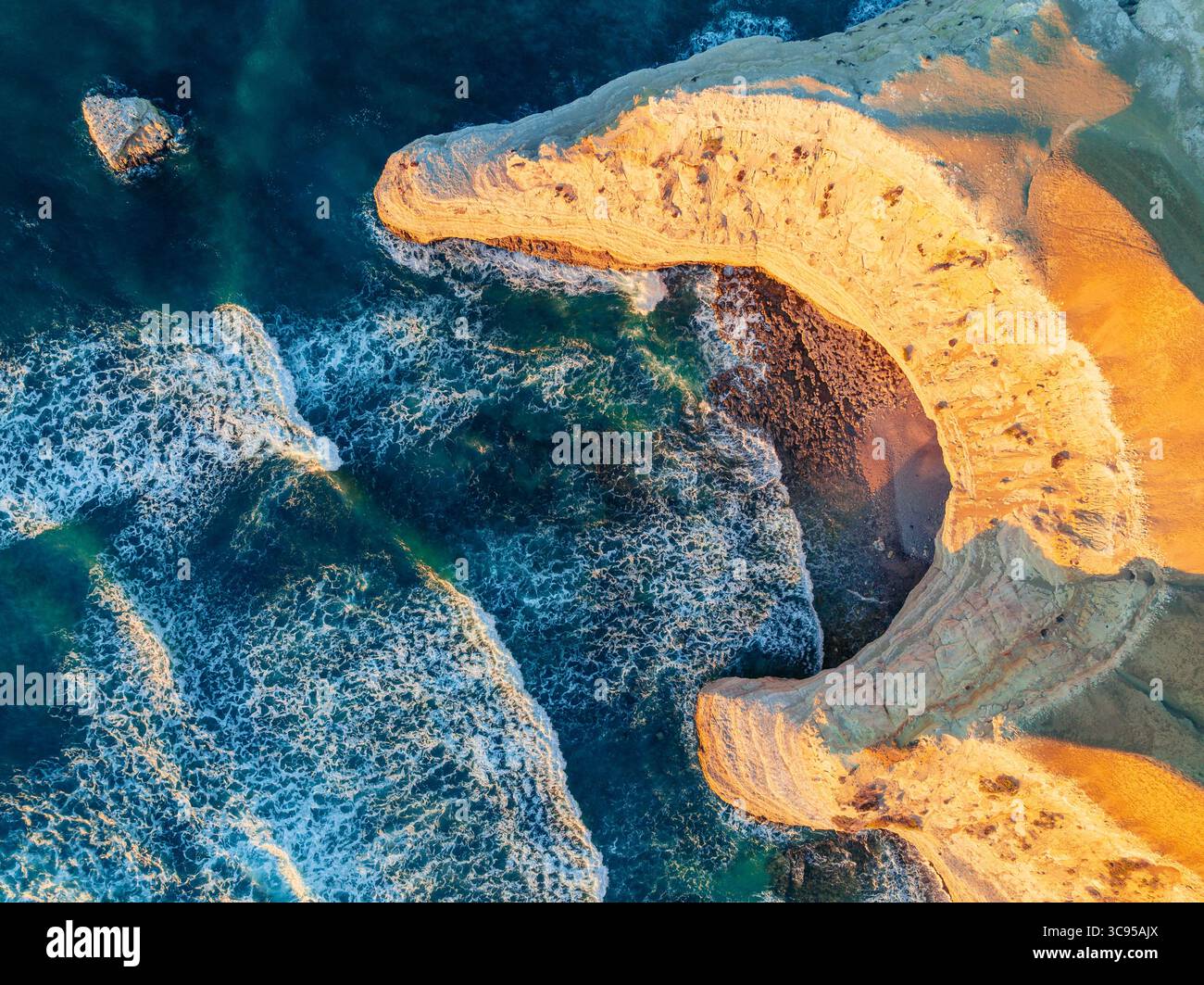 Aerial view of a horseshoe shaped cove below rugged coastal cliffs in ...
