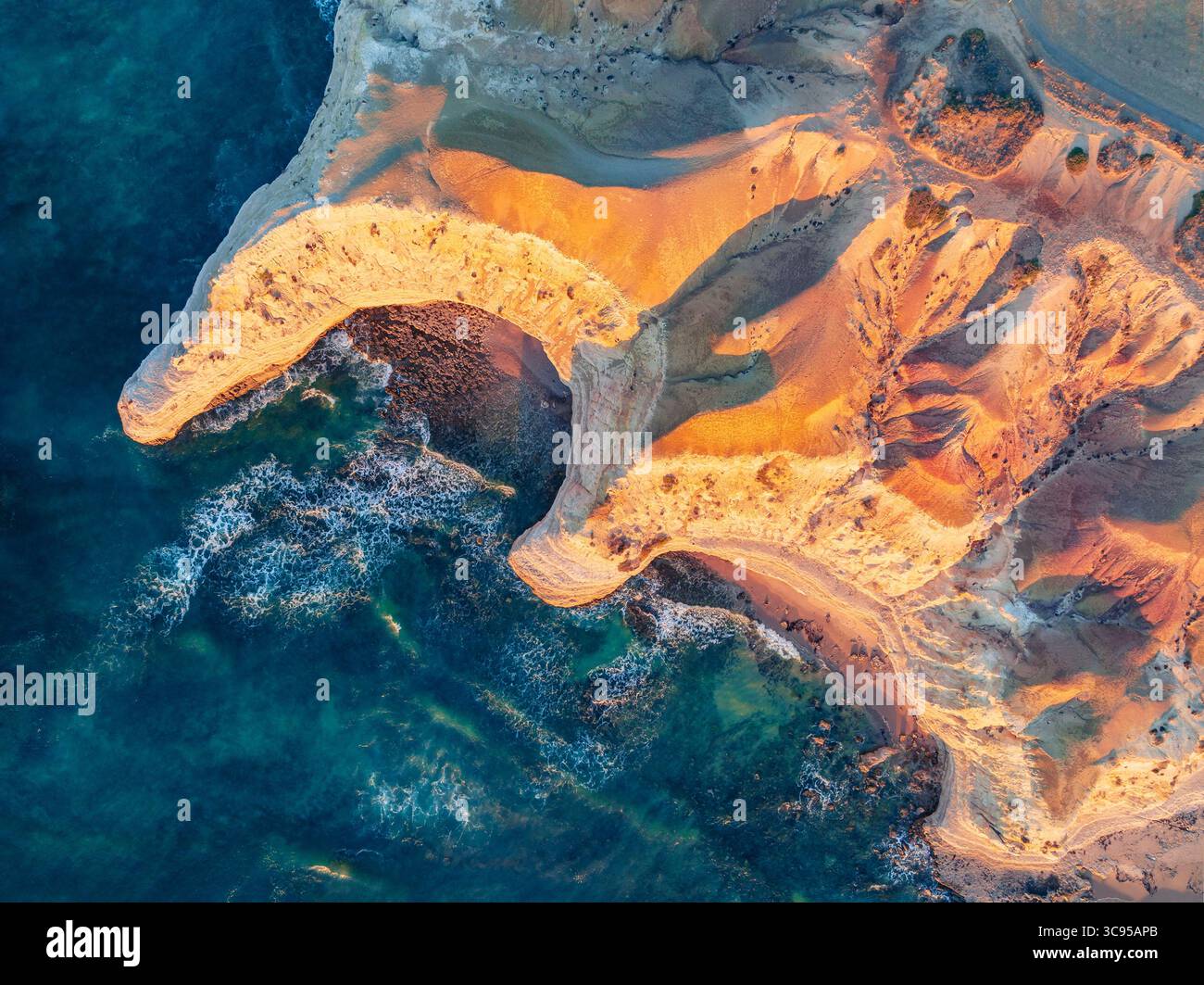 Aerial view of a horseshoe shaped cove below rugged coastal cliffs in ...