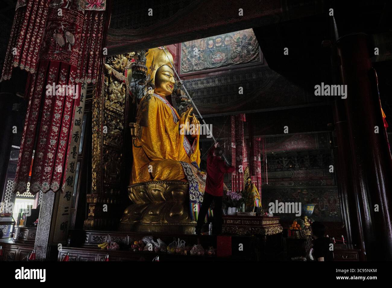 A monk wipes a Buddha statue inside a Tibetan monks' prayer hall at the ...